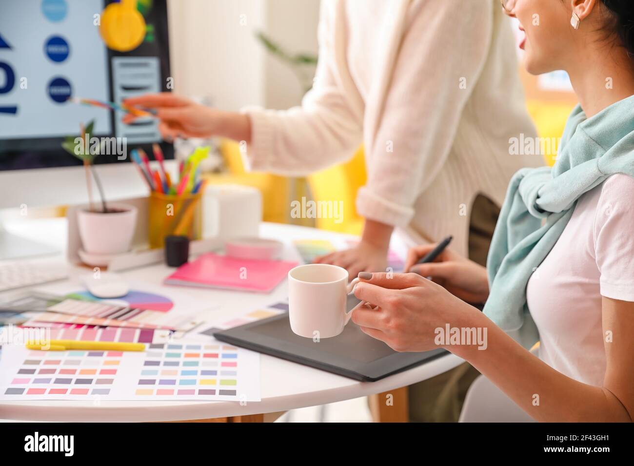 Graphic designer with colleague working in office Stock Photo - Alamy