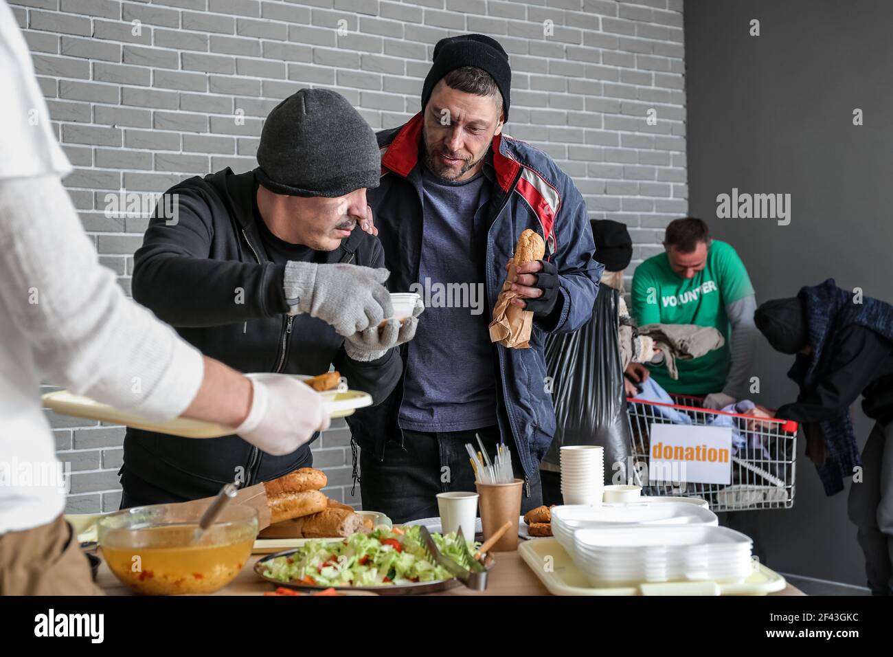 Volunteer giving food to homeless people in warming center Stock Photo ...