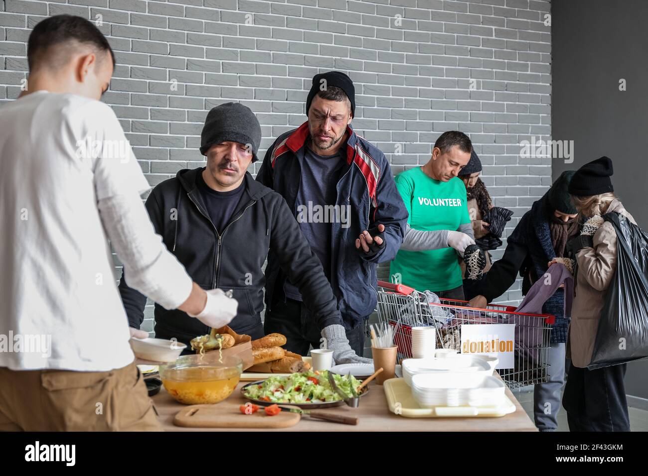 Volunteer giving food to homeless people in warming center Stock Photo ...