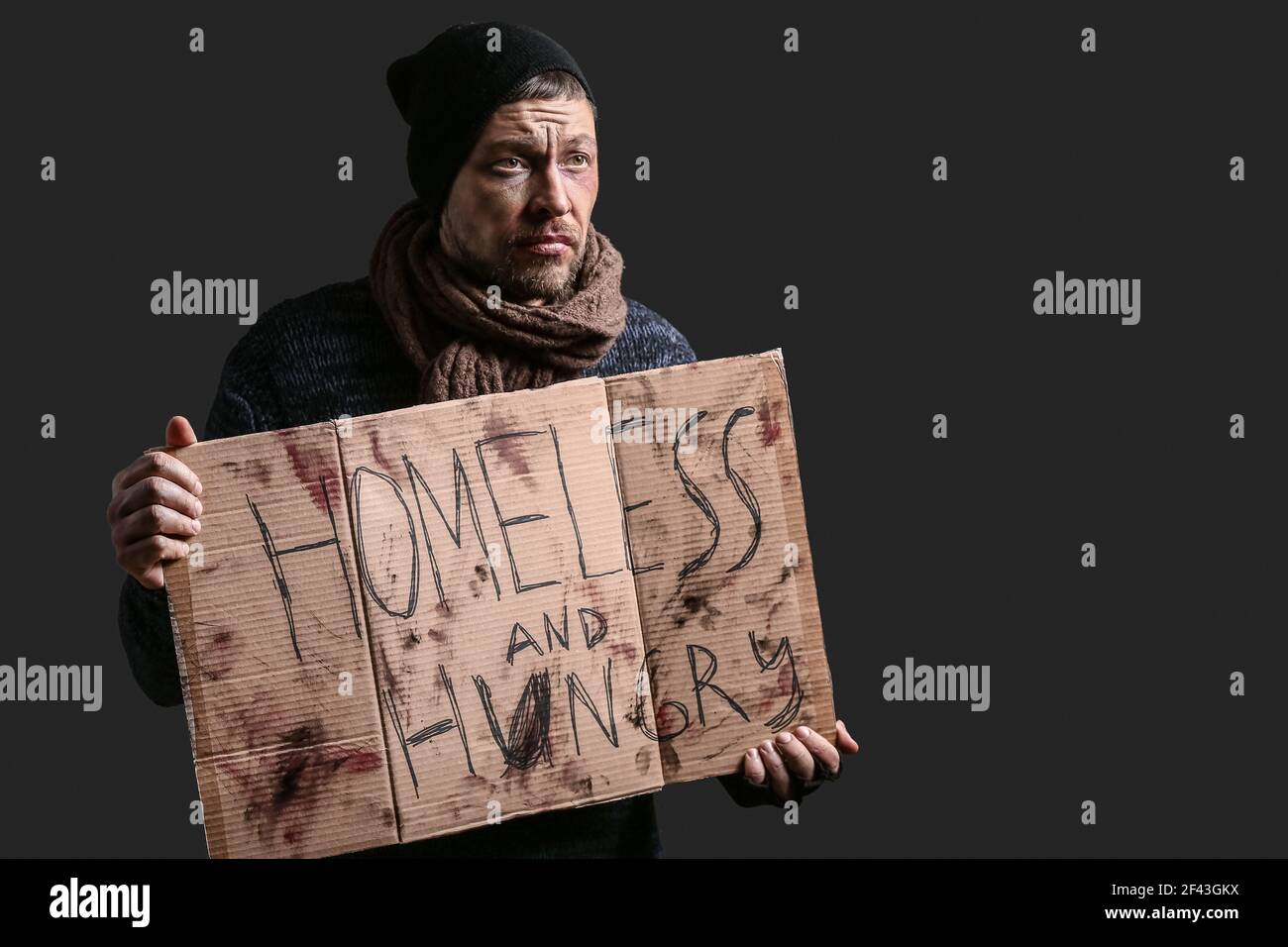Portrait of begging homeless man on dark background Stock Photo - Alamy