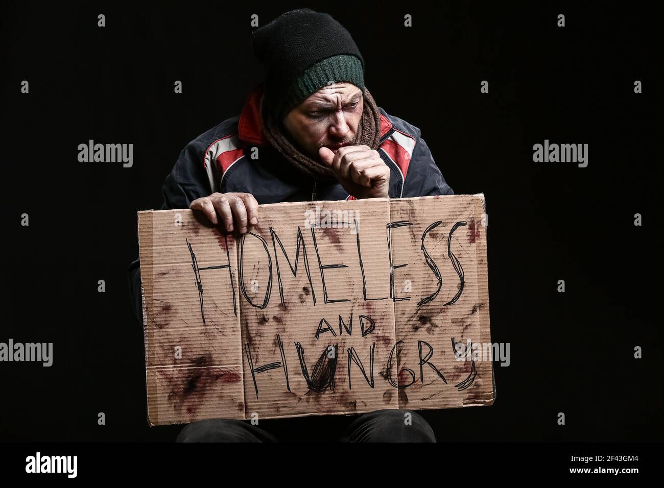 Portrait of begging homeless man on dark background Stock Photo - Alamy