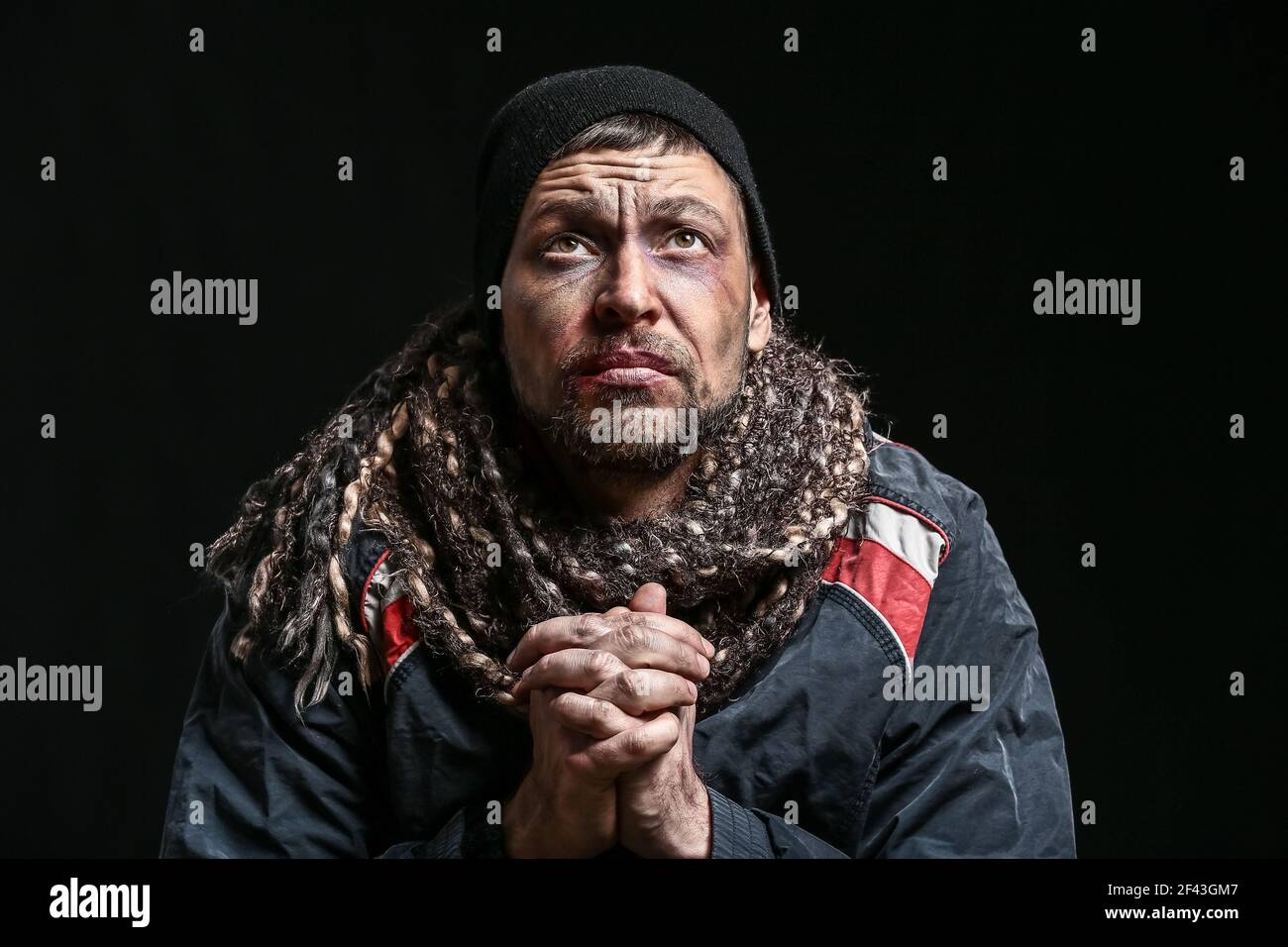 Portrait of praying poor homeless man on dark background Stock Photo ...