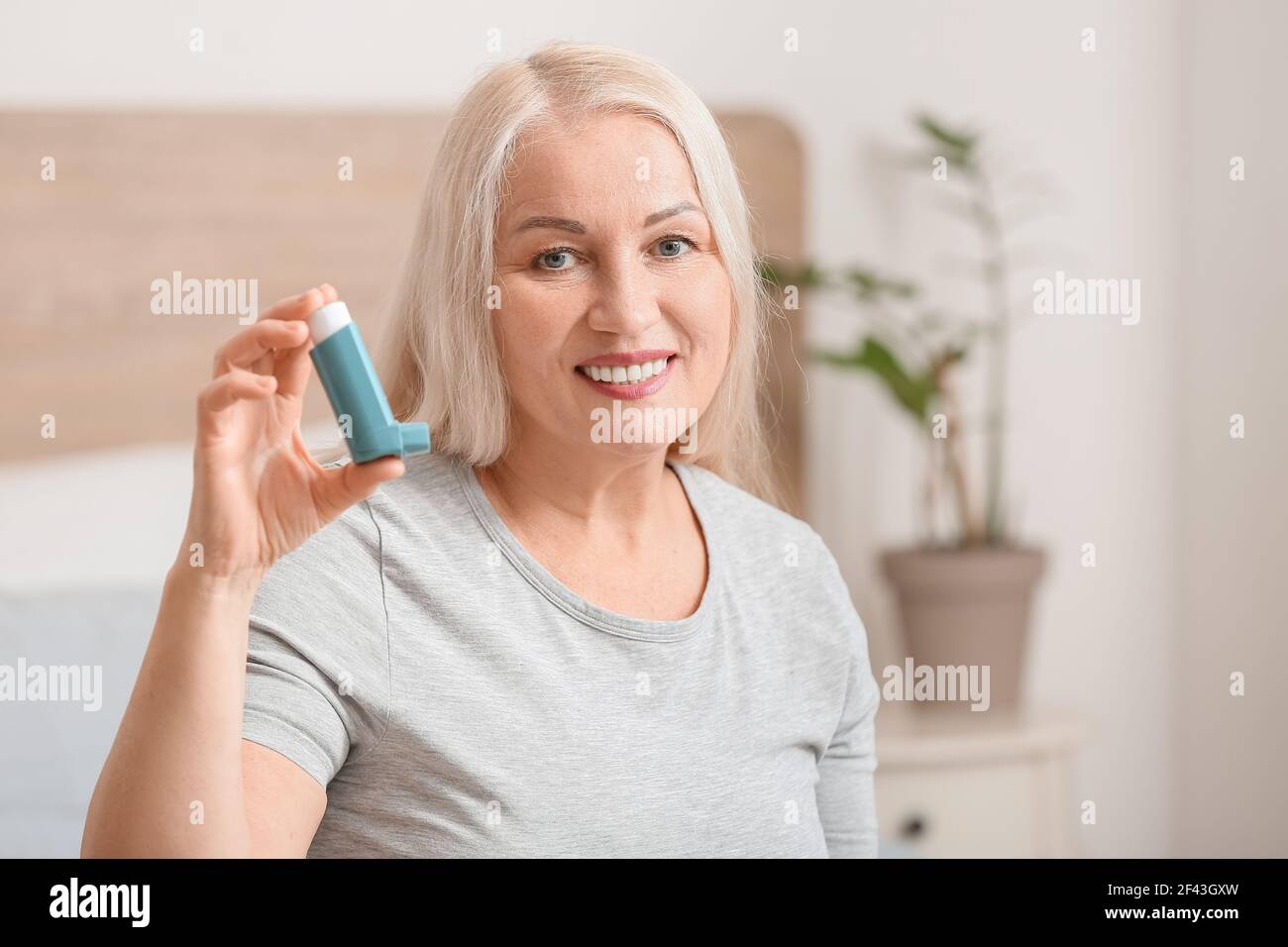 Mature woman with inhaler at home Stock Photo - Alamy
