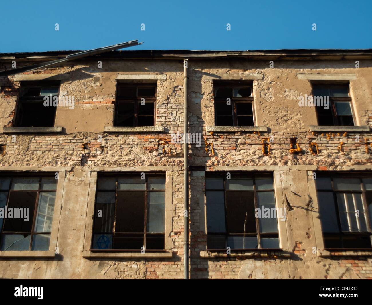Facade of an abandoned old ruin with broken windows and a brick wall with weathered stones Stock ...