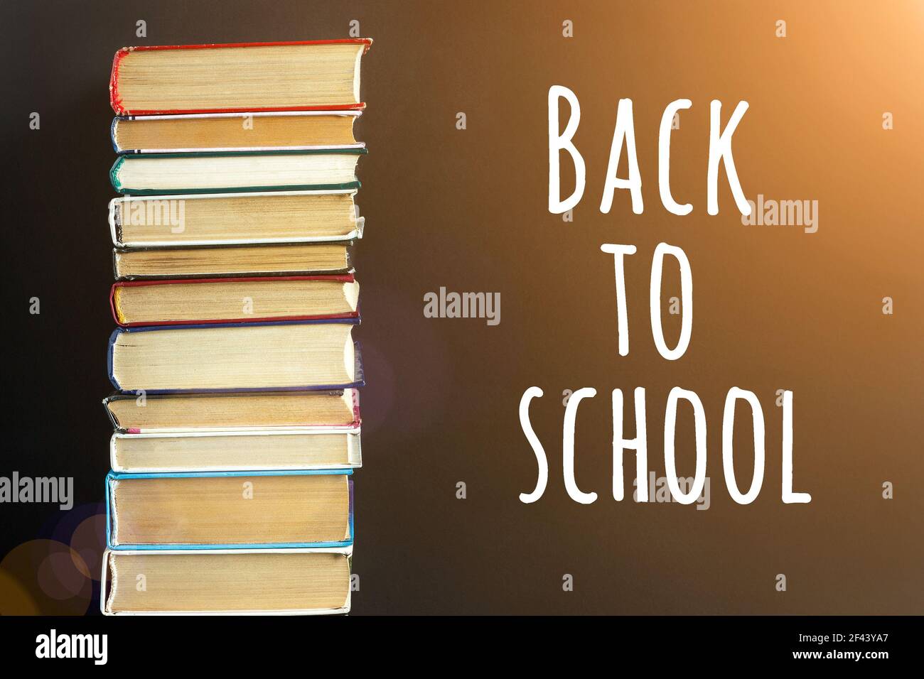 Back to school text on black chalkboard background and stack of books ...