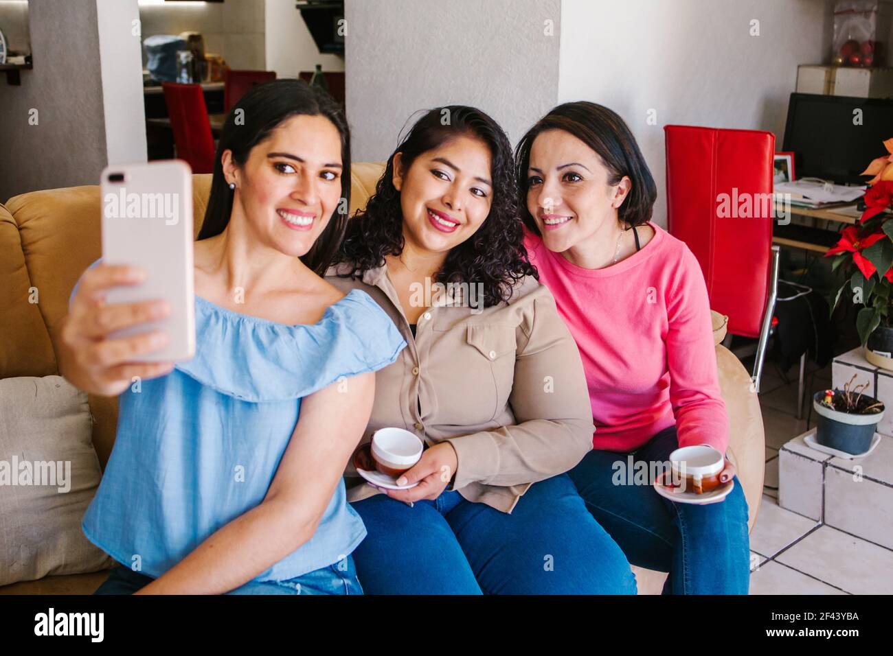 Three happy latin friends women talking and drinking coffee and tea ...