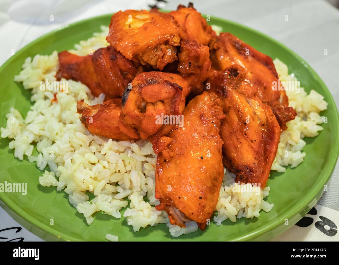 Grilled spicy chicken wings with white brown rice on the green plate ...