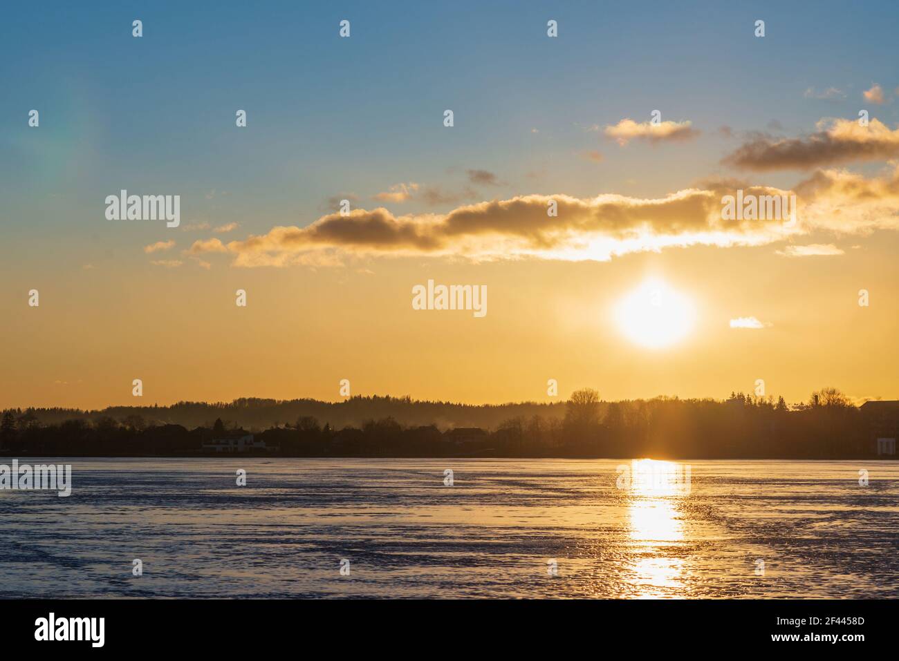 Winter landscape with frozen lake at sunrise or sunset. Lake glistening ...