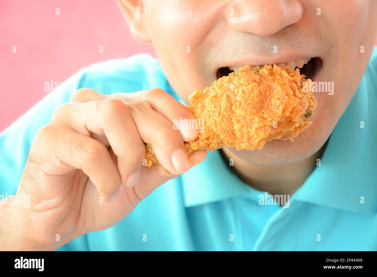 A man biting deep fried chicken leg or drumstick Stock Photo - Alamy