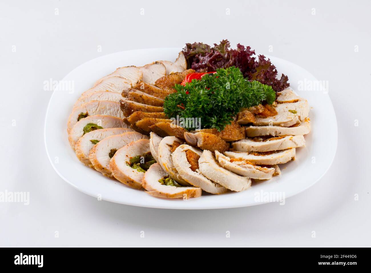 Isolated sliced chicken roll platter with greens Stock Photo - Alamy