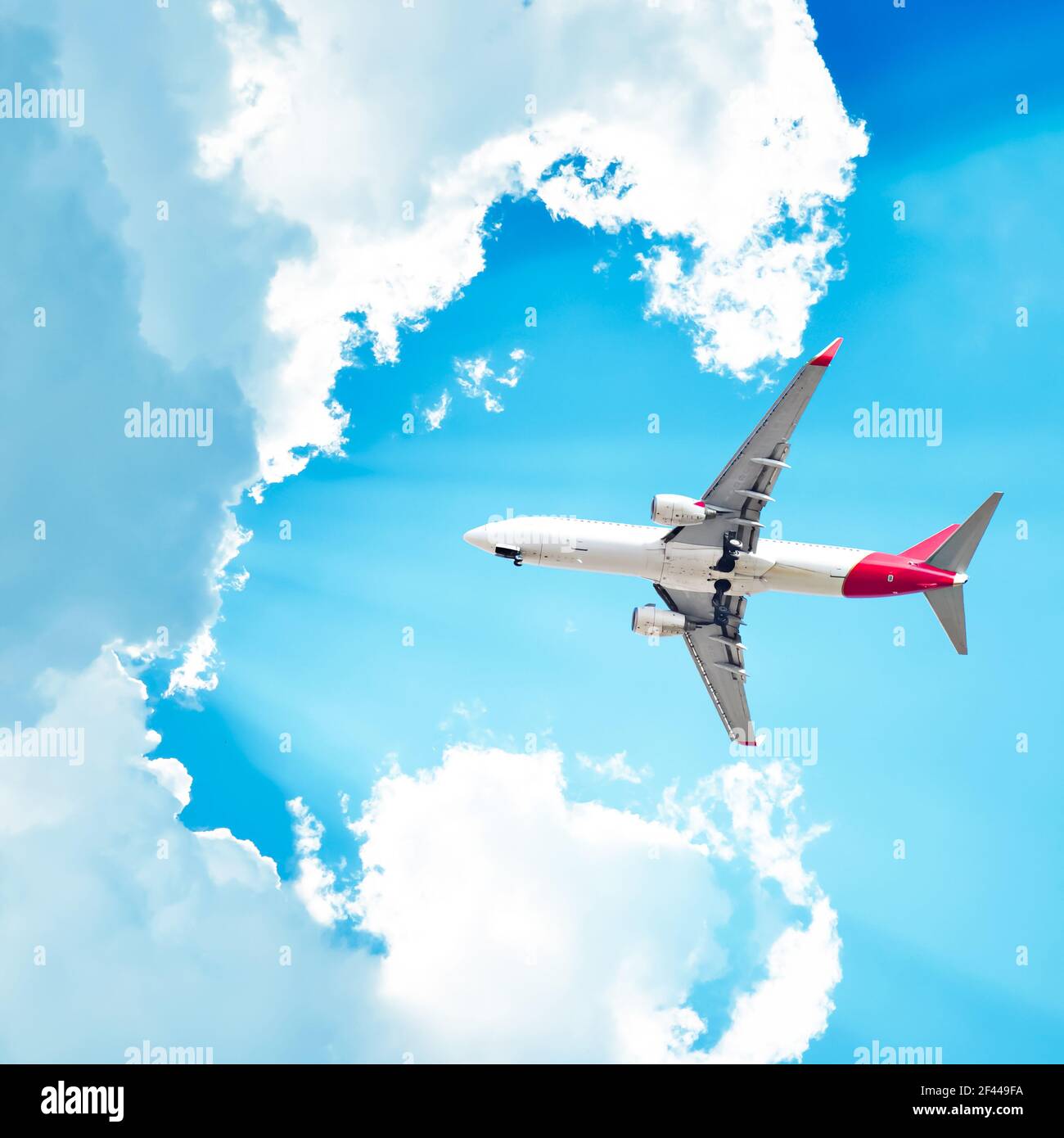 Airplane flying in sunny sky with clouds Stock Photo - Alamy