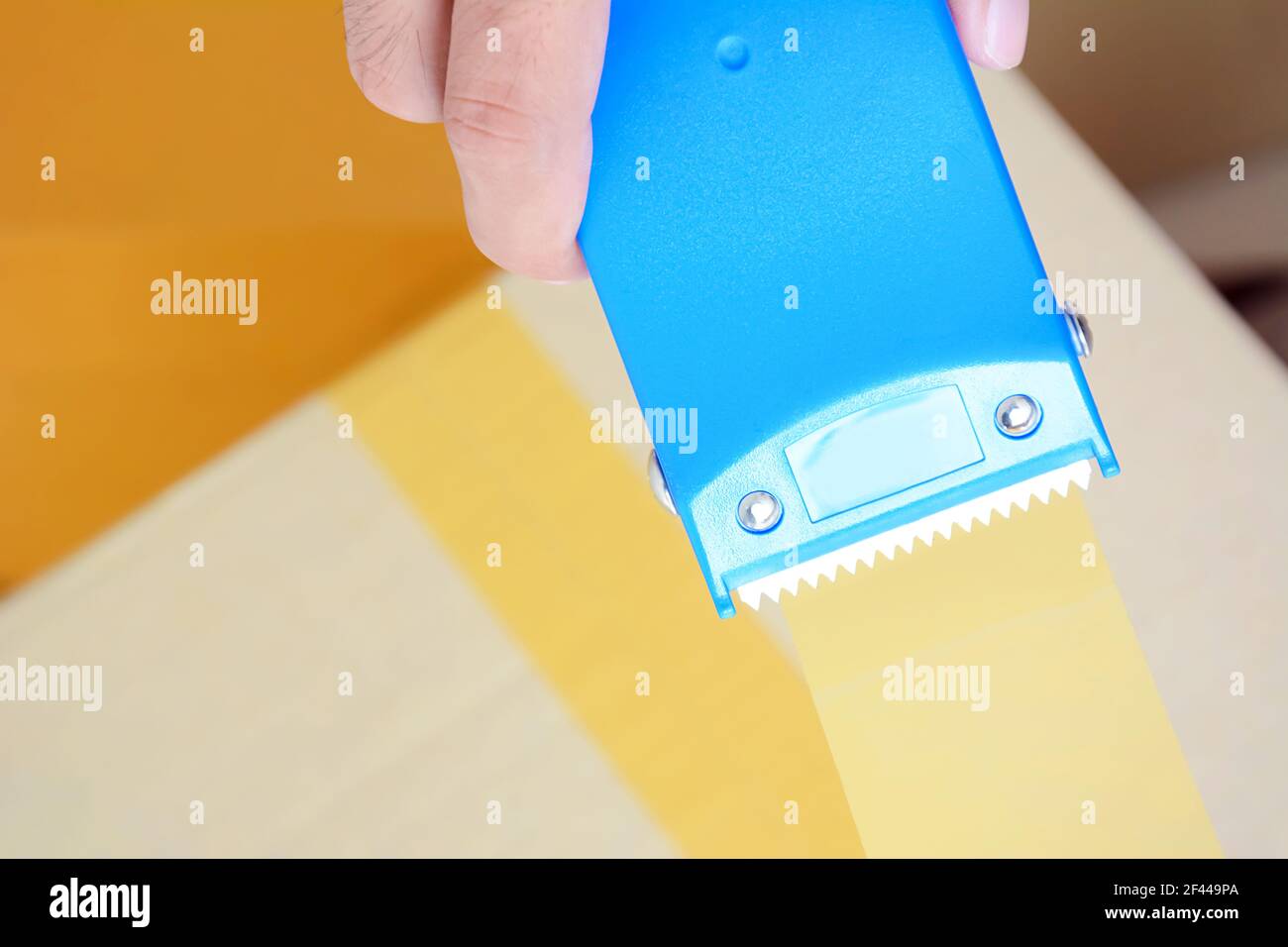 Hand holding masking tape dispenser, taping a box Stock Photo - Alamy