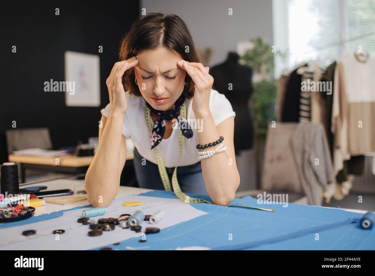 Tired dressmaker a having headache at workshop Stock Photo - Alamy