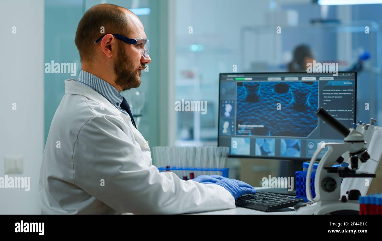 Scientist in lab coat analysing blood sample from test tube. Viorolog ...
