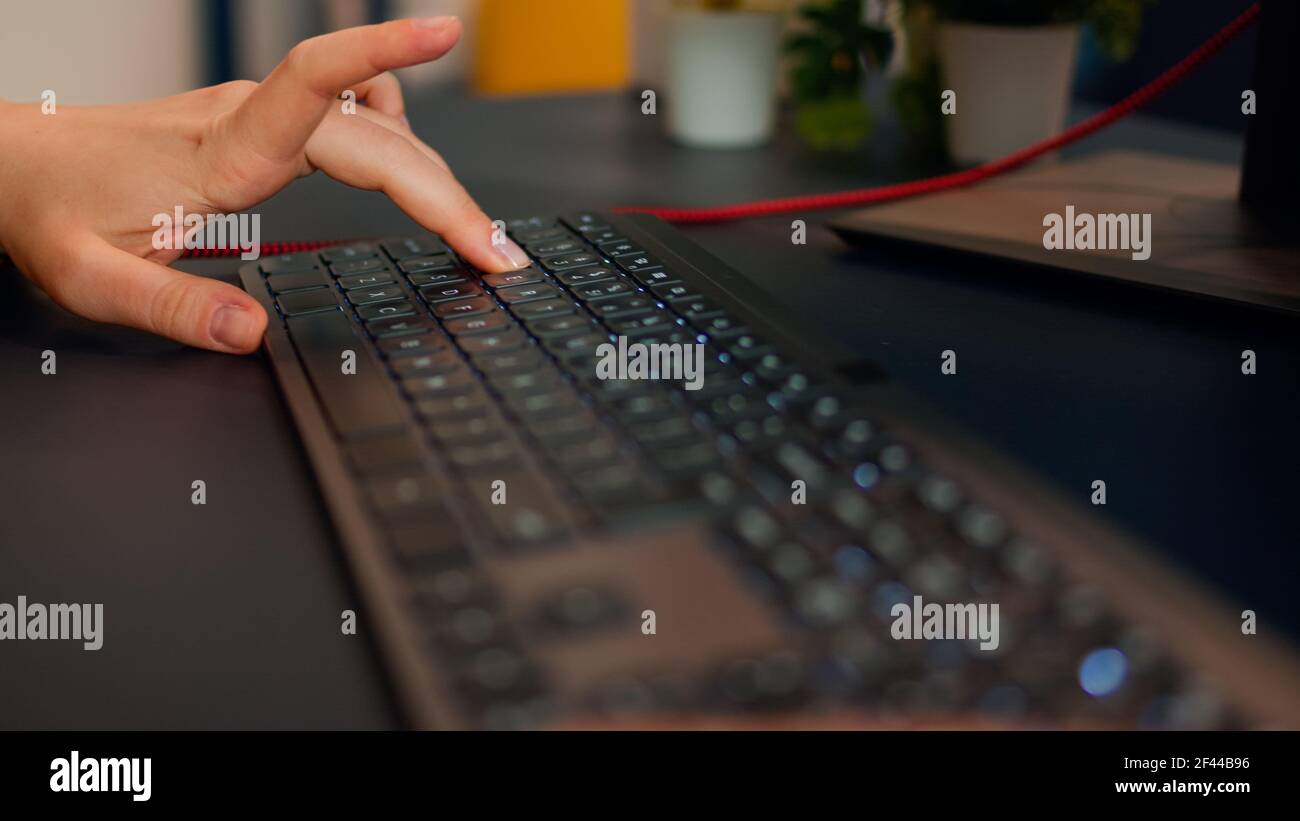Close-up on hands of woman gamer playing video game using RGB keyboard ...
