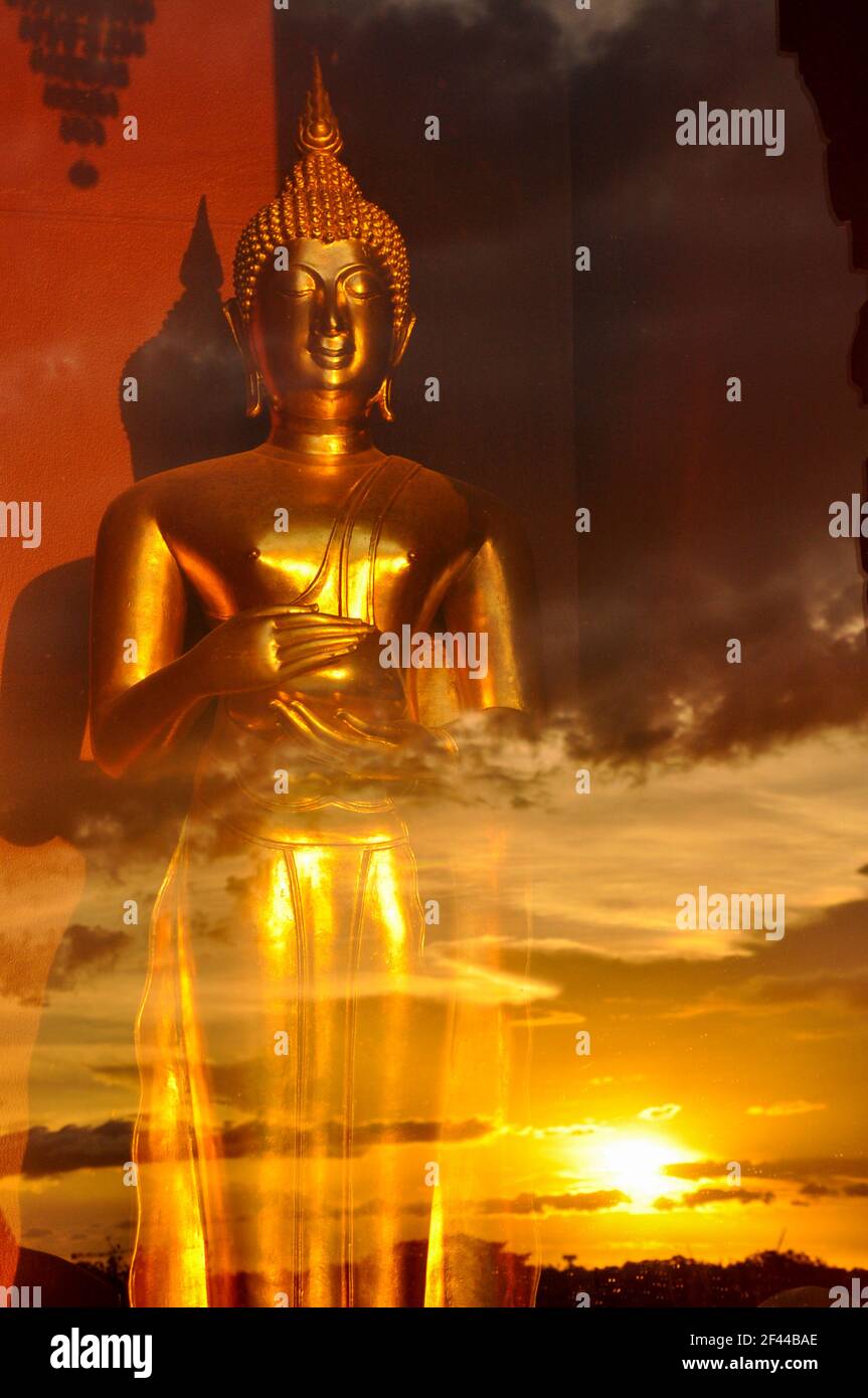 Golden Buddha statue in the glass room with twilight sky reflection ...
