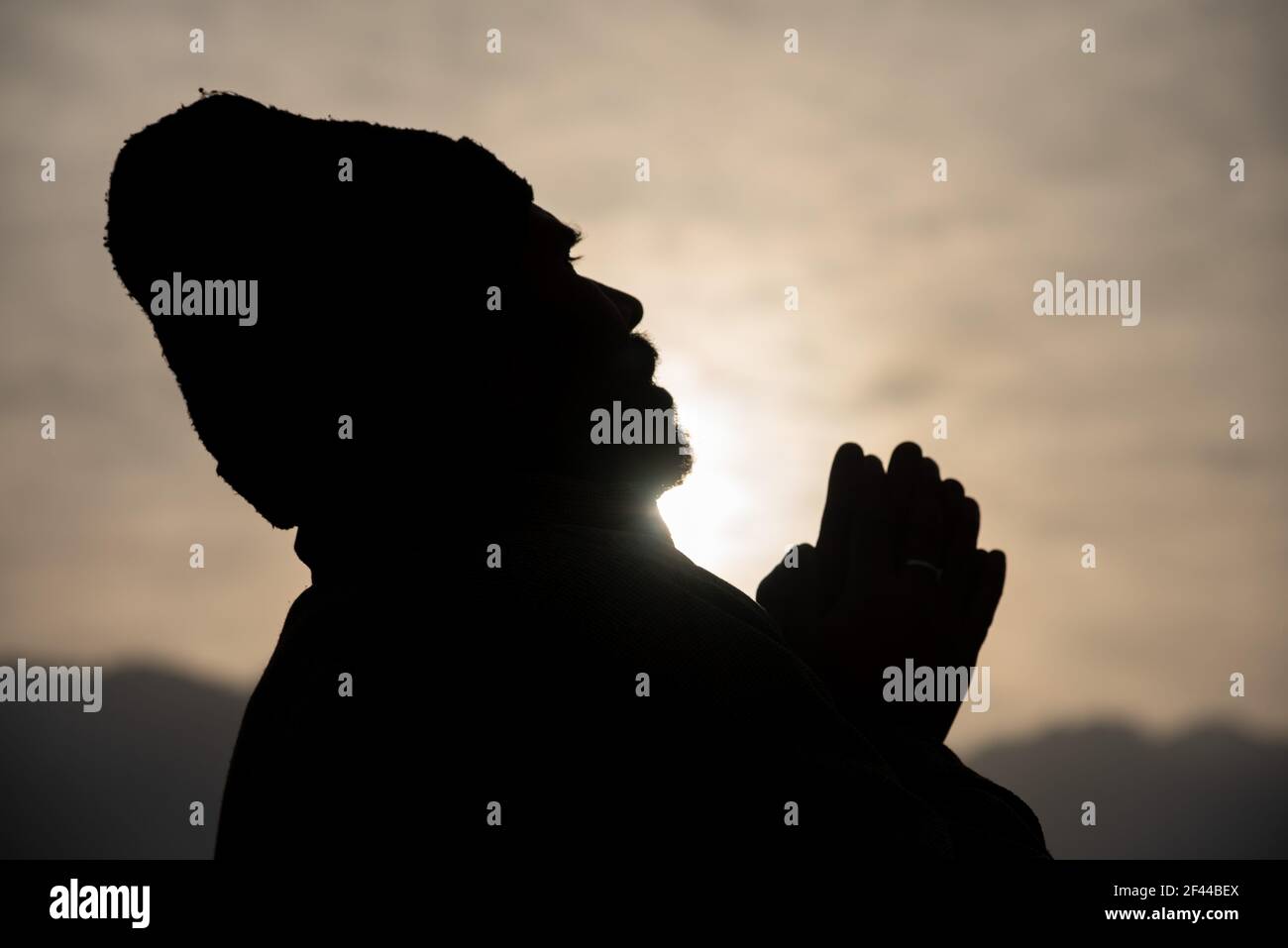 A silhouette of Kashmiri Muslim devotee raising hands while beseeching ...
