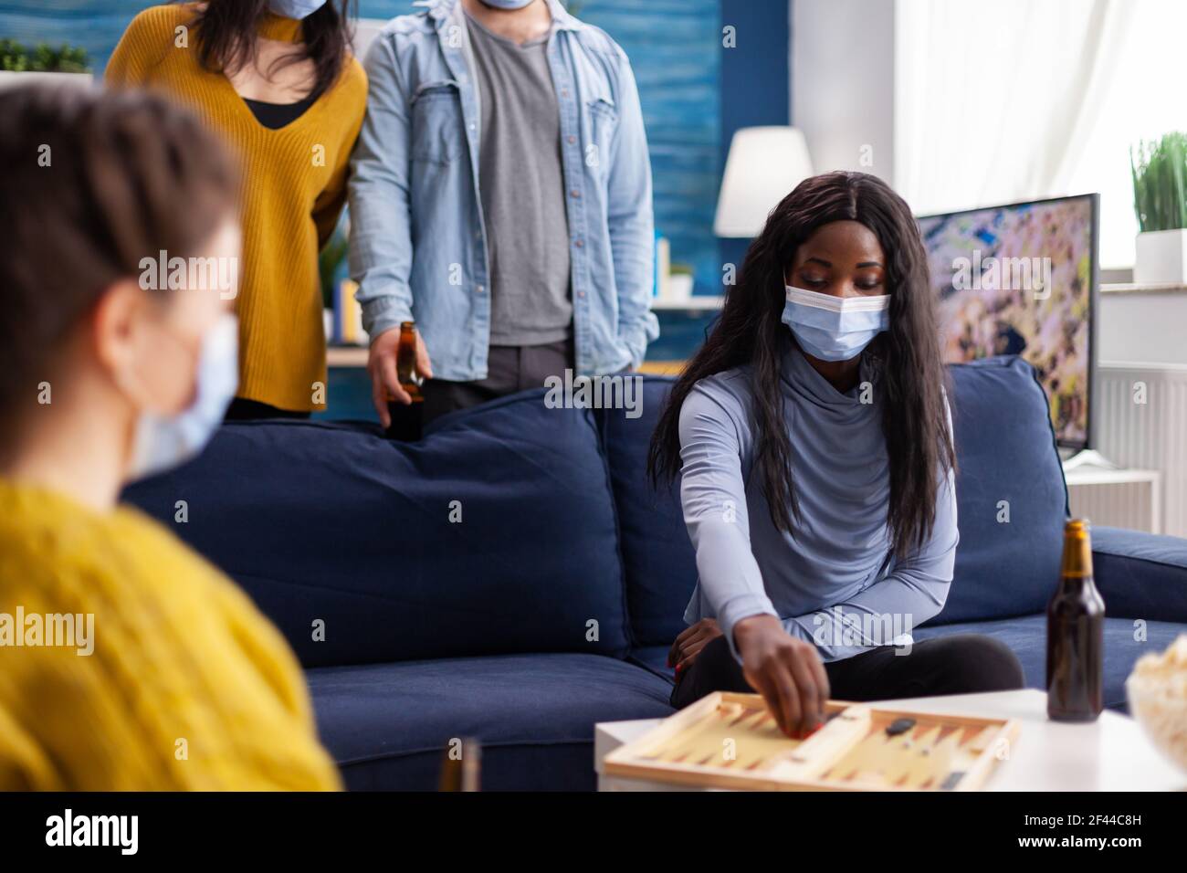African woman competing with friends playing backgammon wearing face ...