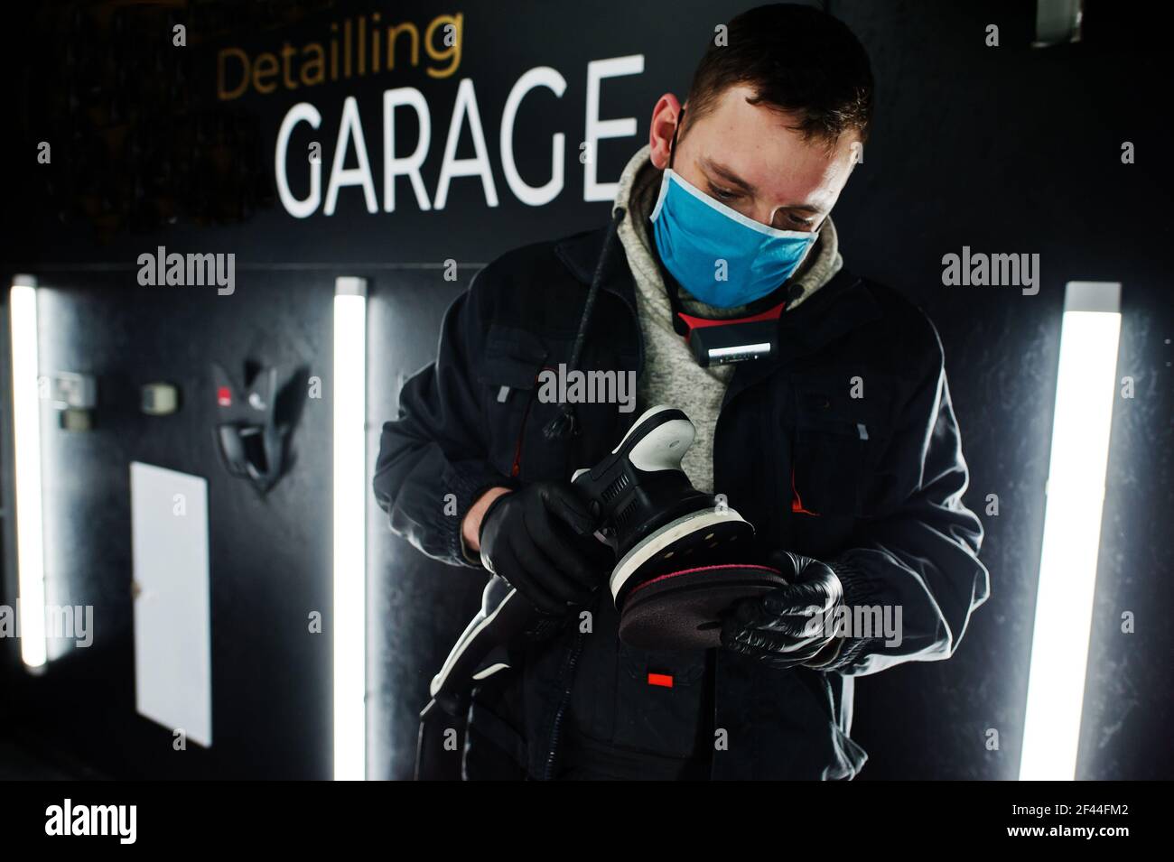 Car detailing concept. Man in face mask with orbital polisher in repair ...