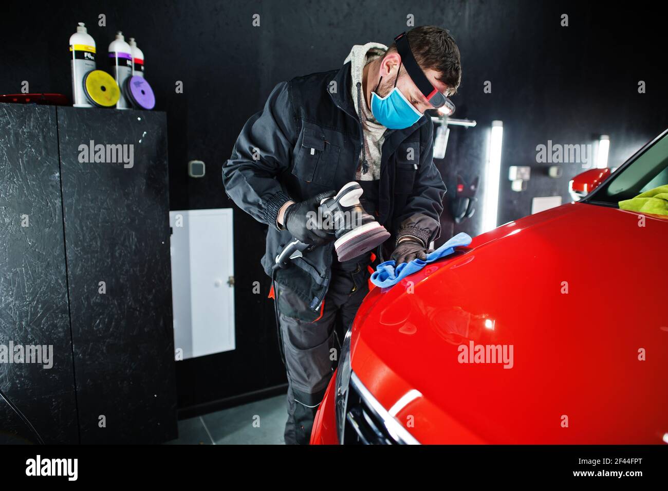 Car detailing concept. Man in face mask with orbital polisher in repair ...
