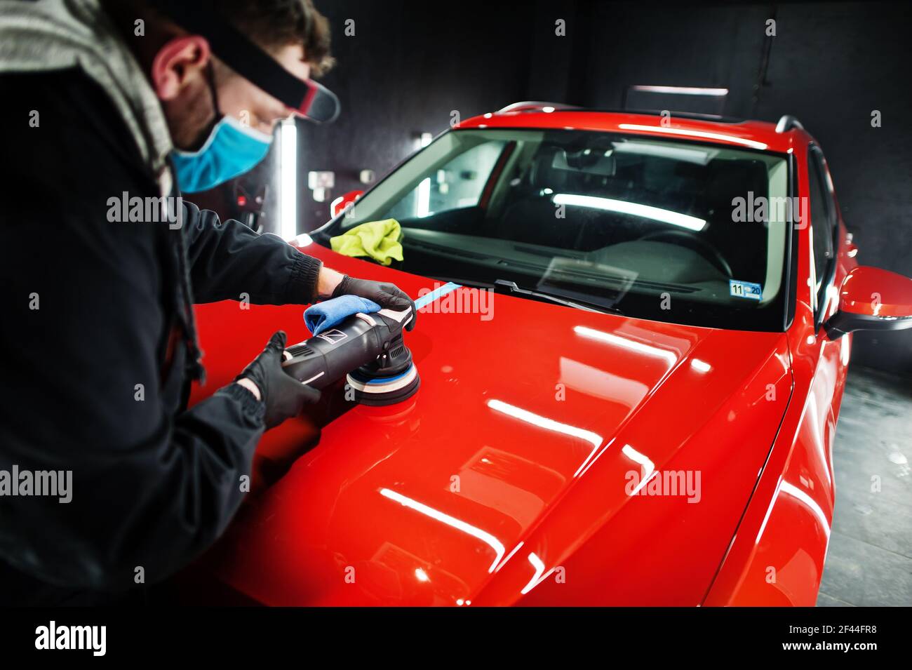 Car detailing concept. Man in face mask with orbital polisher in repair ...