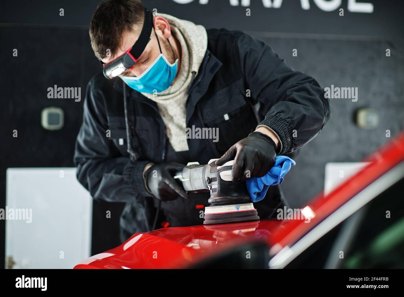 Car detailing concept. Man in face mask with orbital polisher in repair ...