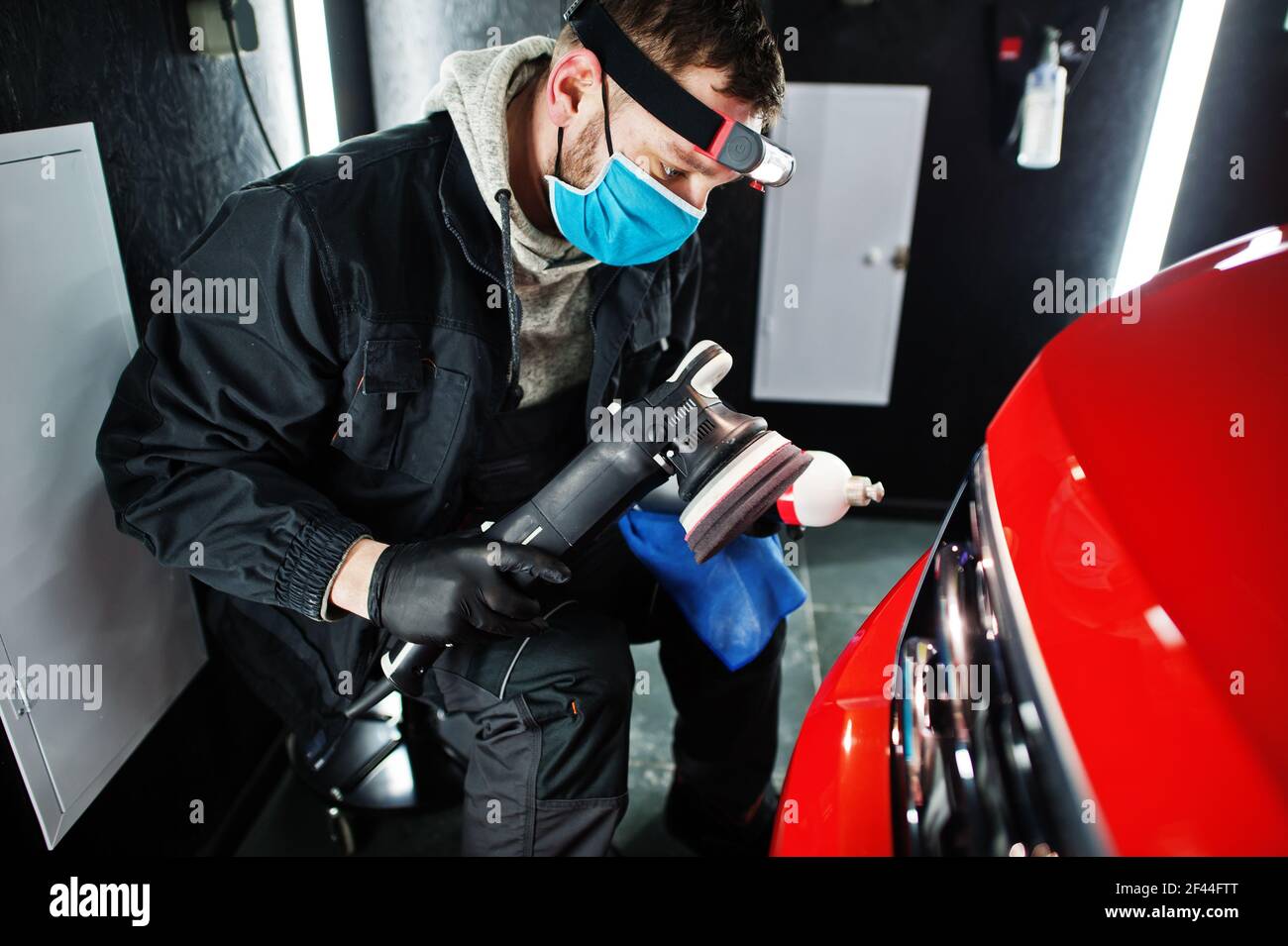 Car detailing concept. Man in face mask with orbital polisher in repair ...
