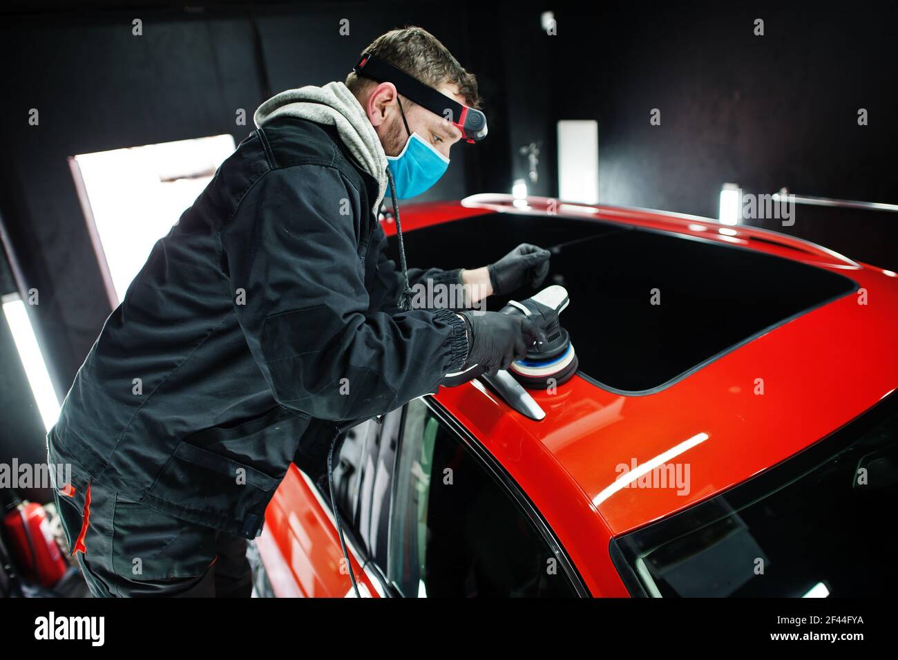 Car detailing concept. Man in face mask with orbital polisher in repair ...
