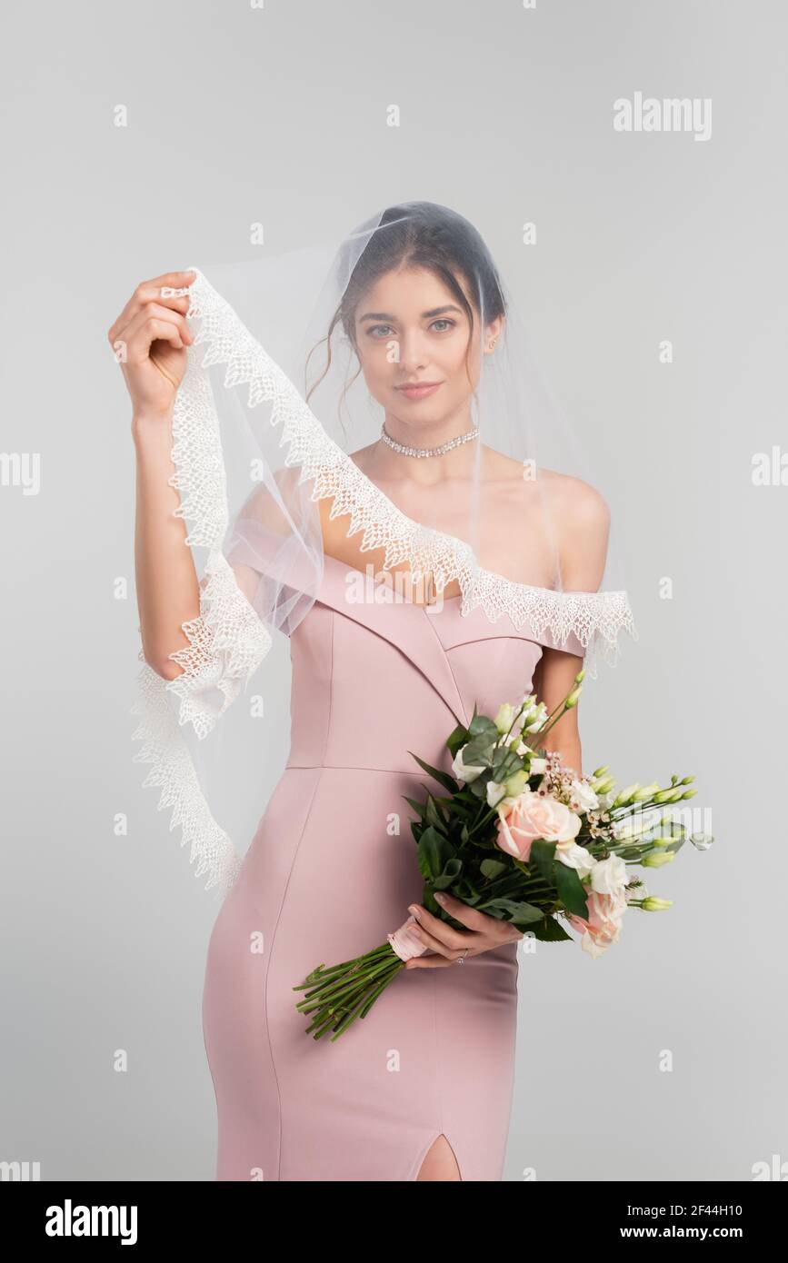 sensual woman touching veil while holding wedding bouquet isolated on grey Stock Photo - Alamy