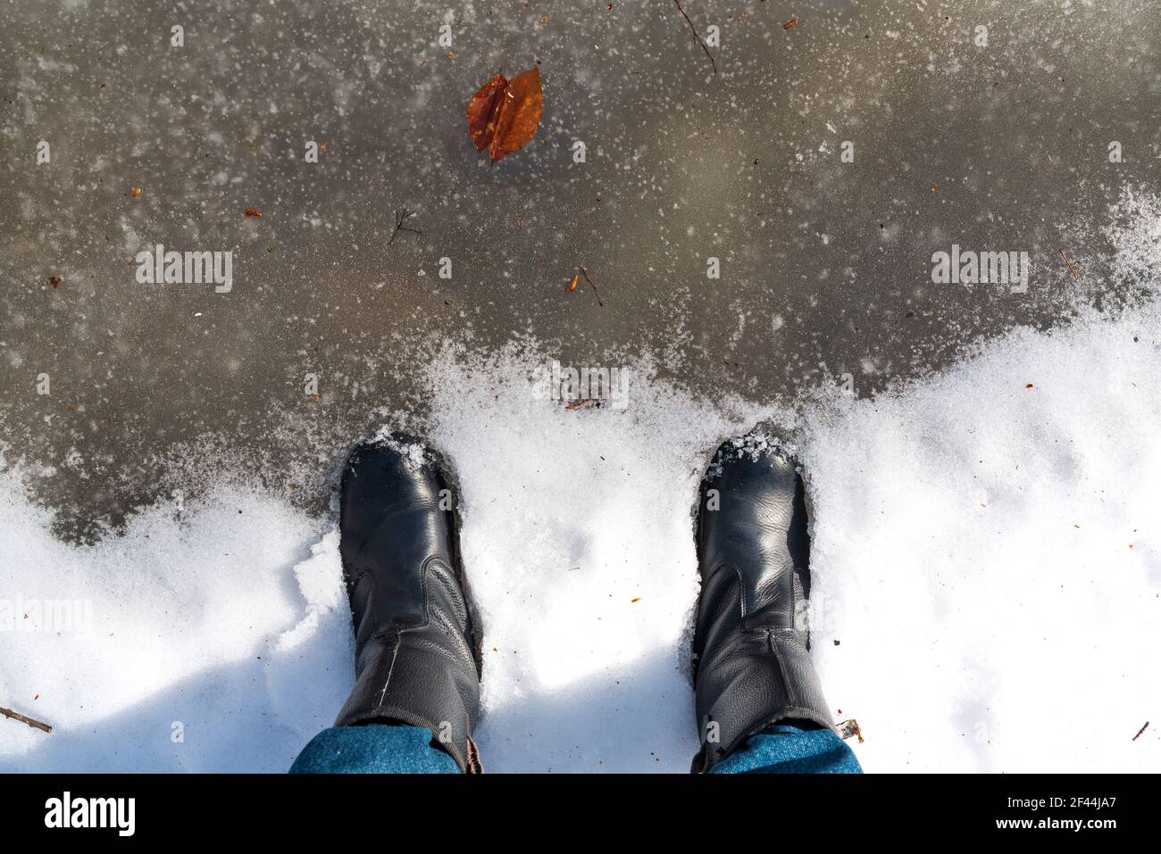 Feet in boots in a frozen puddle Stock Photo - Alamy