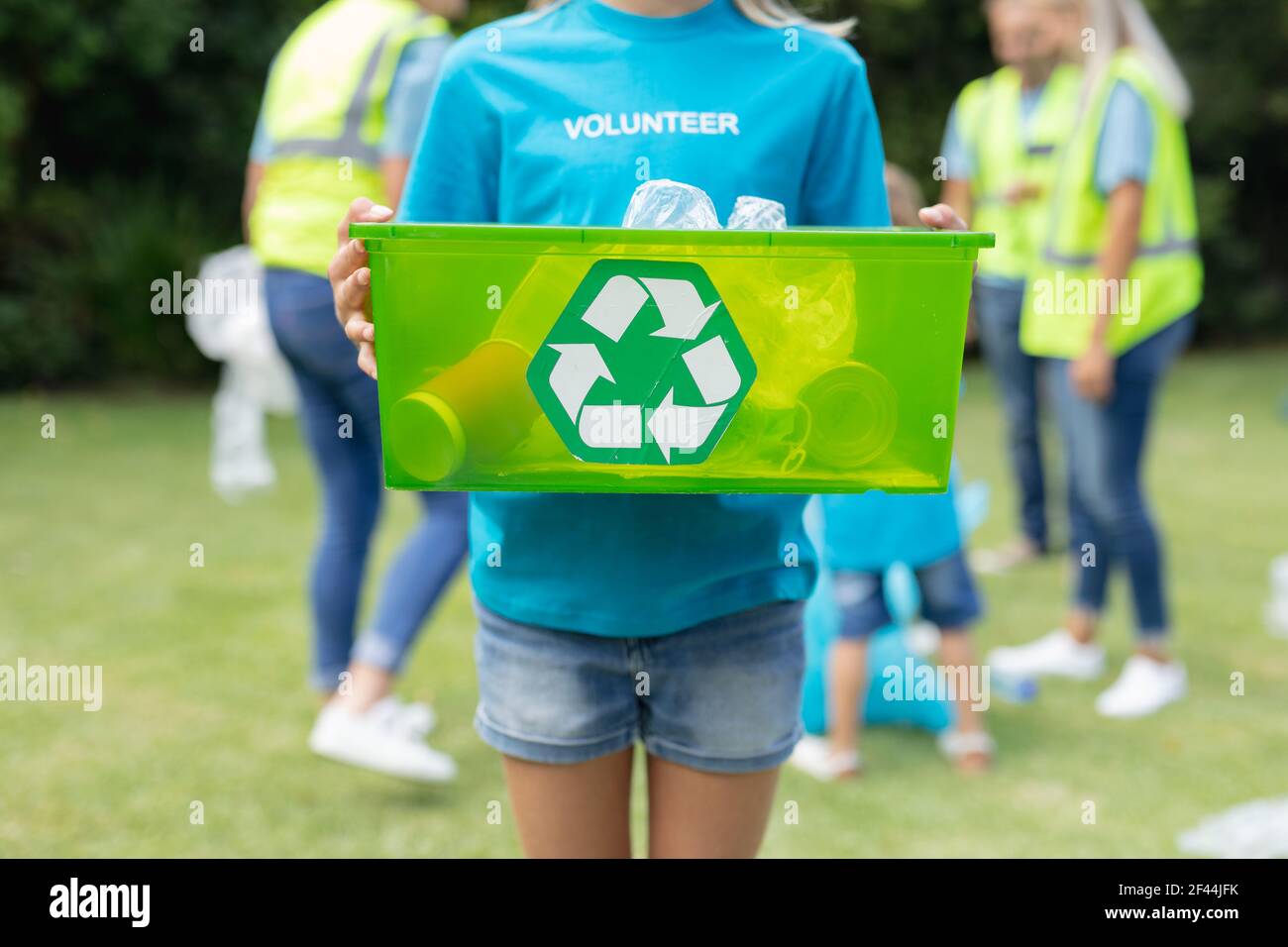 Caucasian girl holding recycling box with group of men and women ...