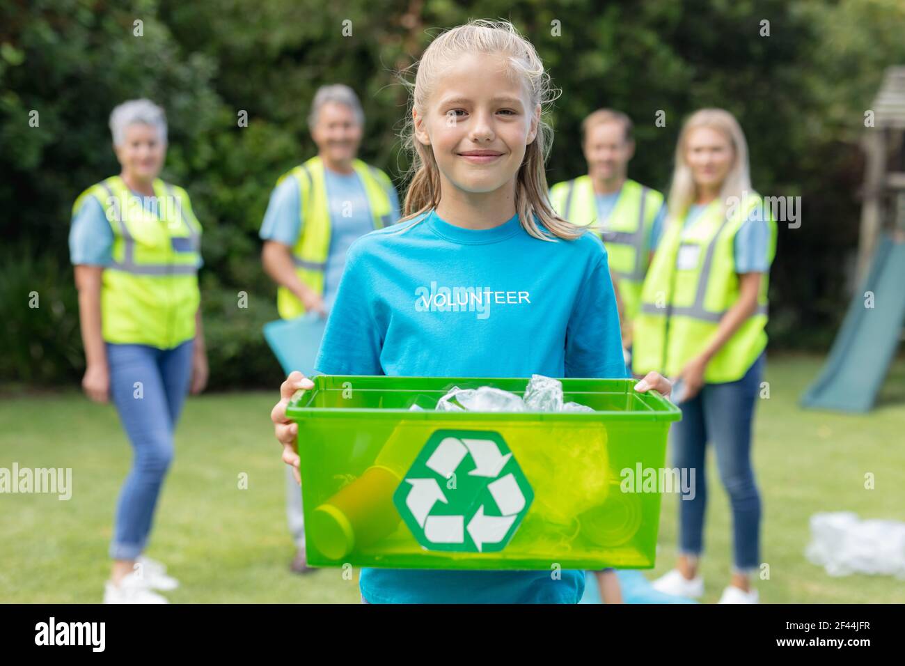 Caucasian girl holding recycling box with group of men and women ...