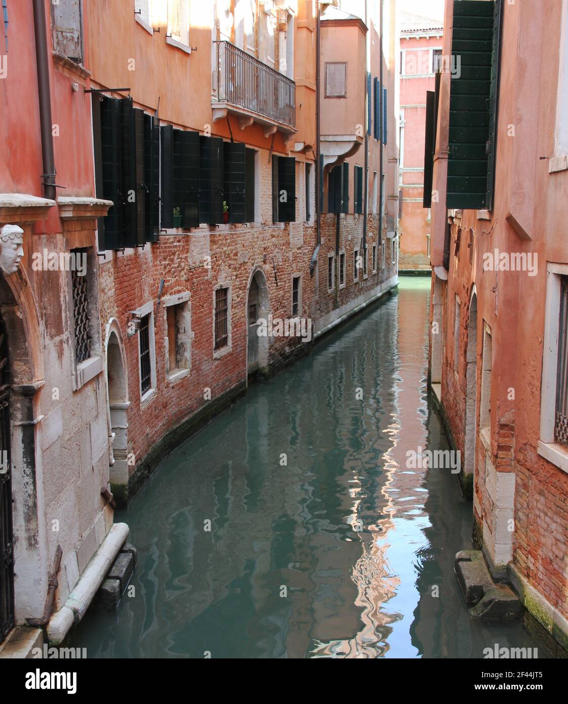 A canal street in Venice. A narrow water alley with high old houses ...