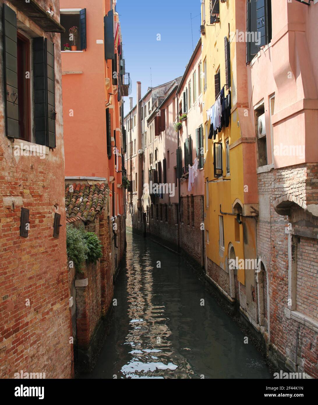 A canal street in Venice. A narrow water alley with high old houses ...