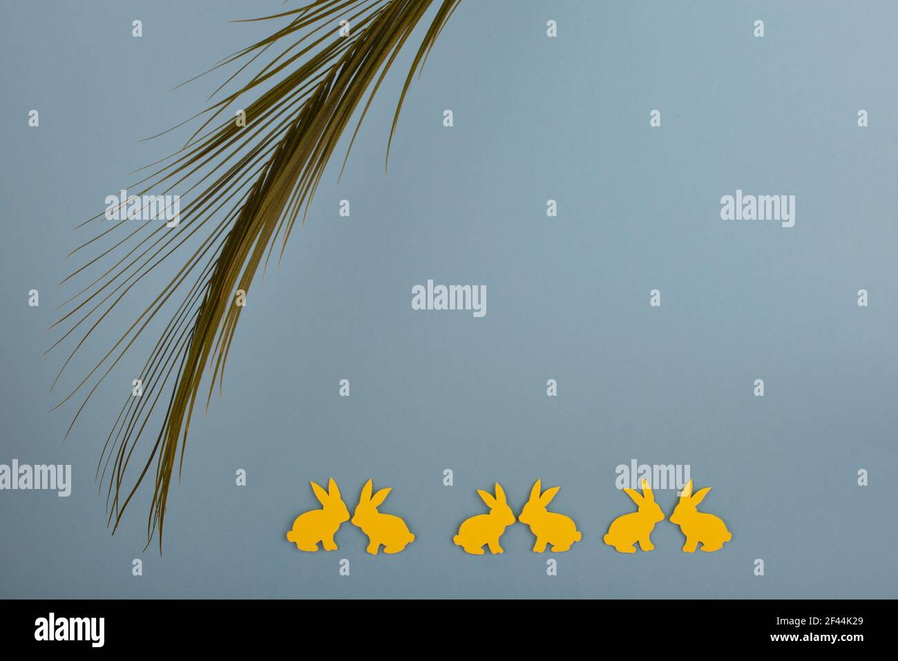 Palm Sunday concept. Palm tree branch and yellow bunnies on gray ...