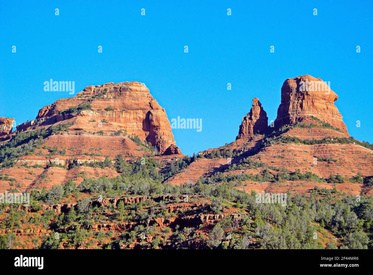 A beautiful view of red rock mountains with juniper trees at the foot ...