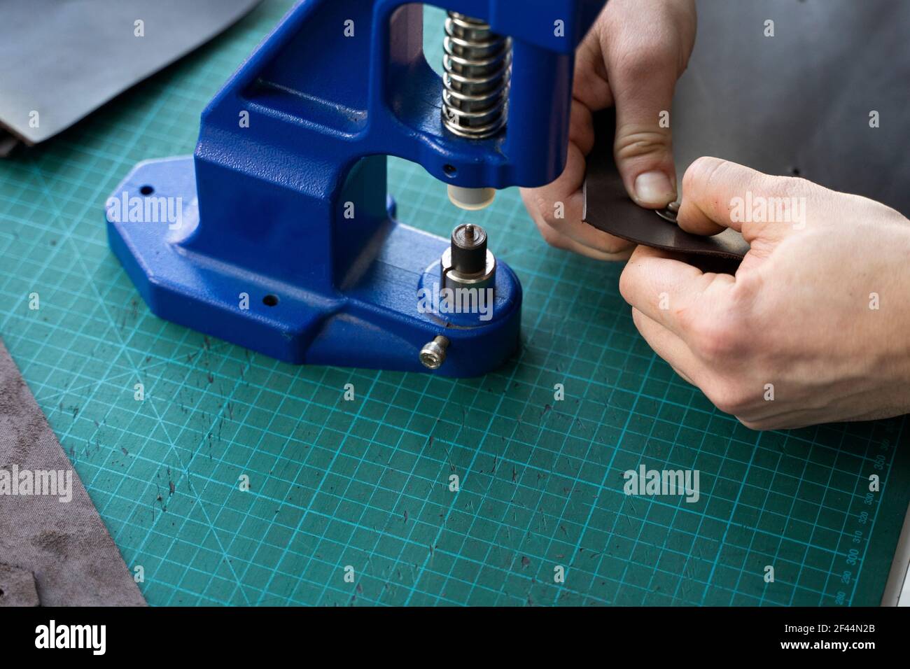 Artisan using hand press for setting snaps in leather for makes a ...