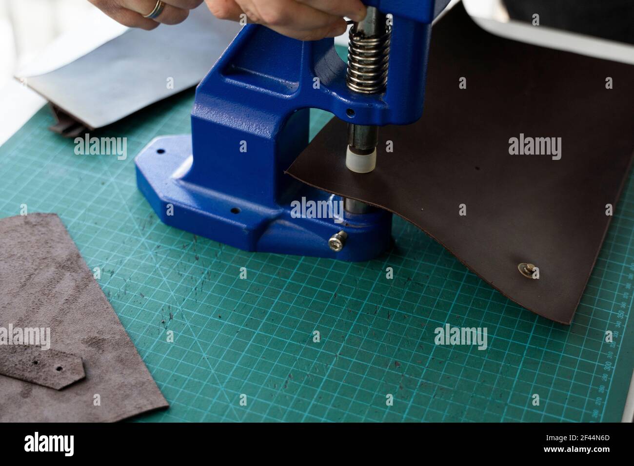 Artisan using hand press for setting snaps in leather for makes a ...