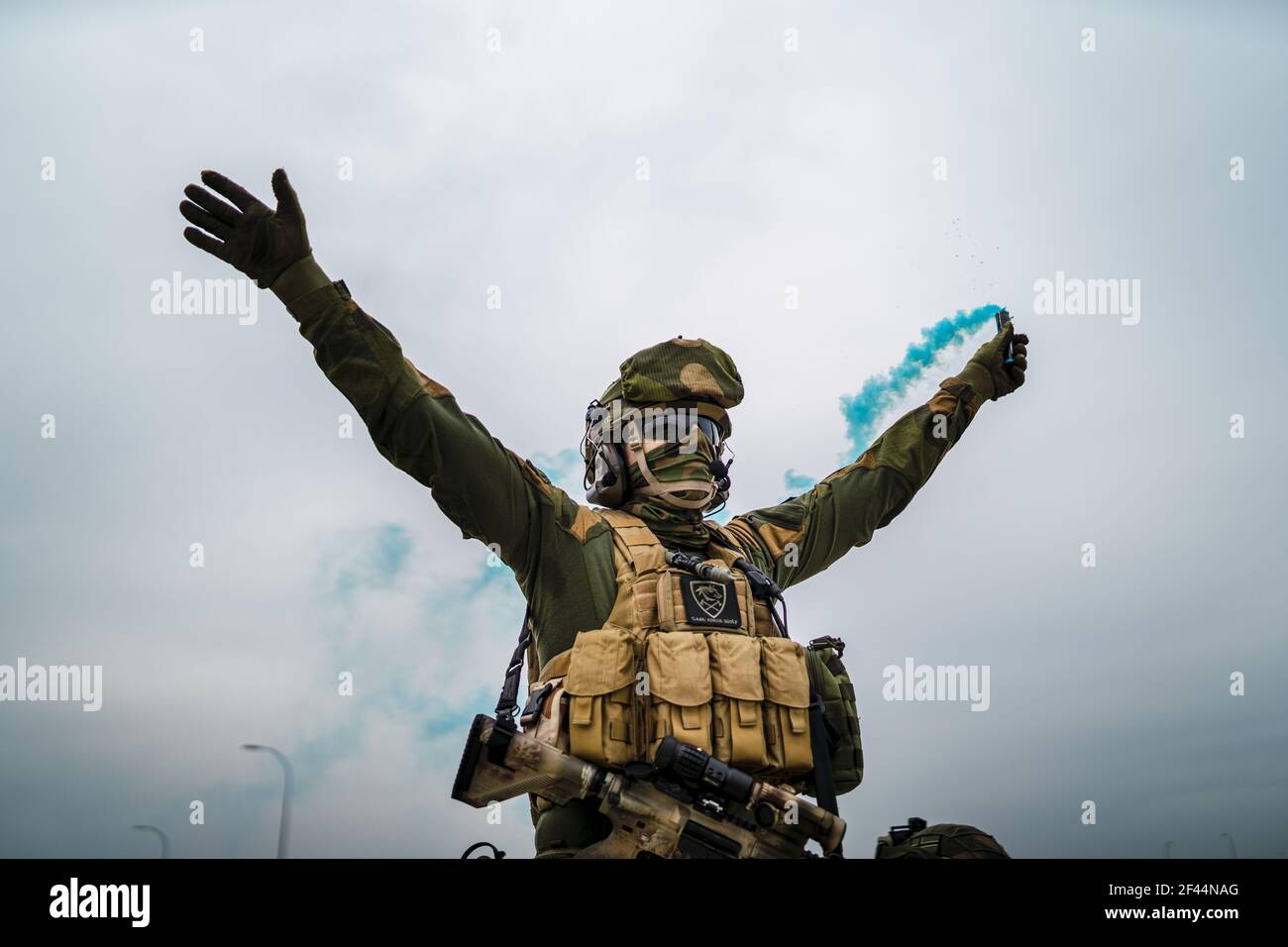 A shallow focus of an armed special force soldier holding a blue smoke ...