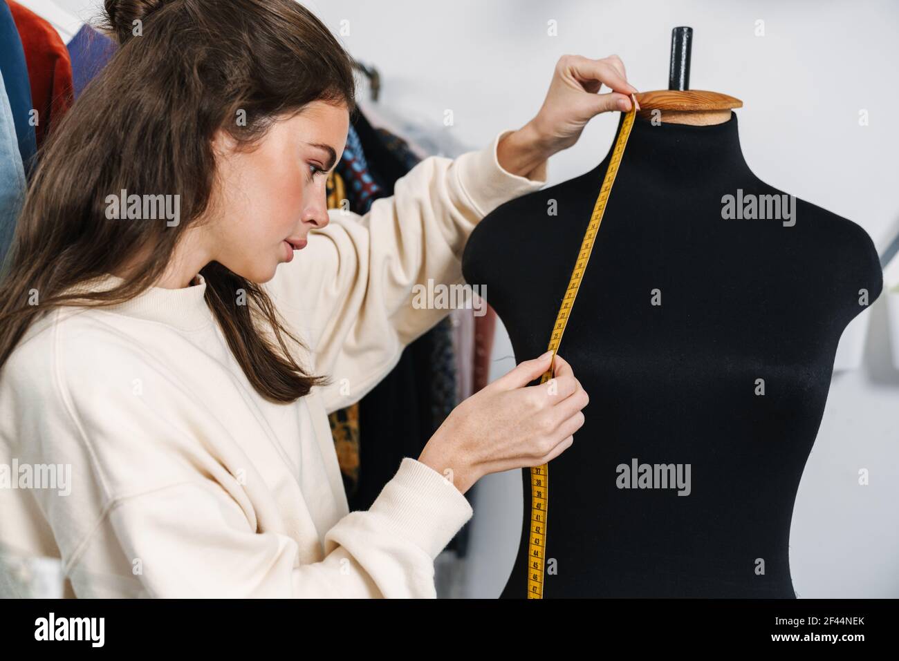 Portrait of a young designer woman with mannequin or dummy working in ...