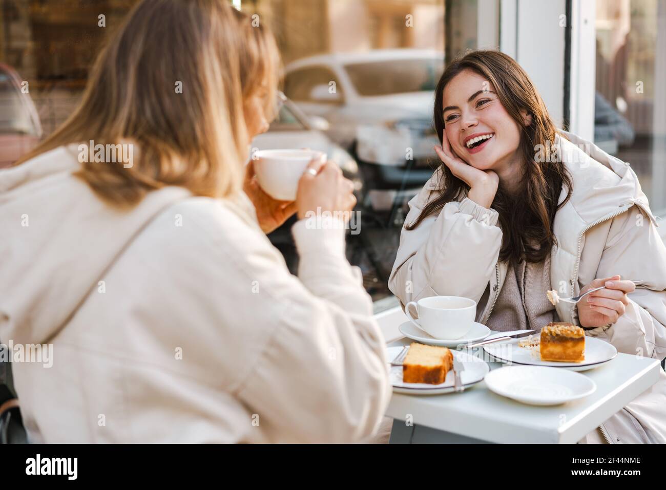 Two attractive young women having lunch at the cafe outdoors, eating ...
