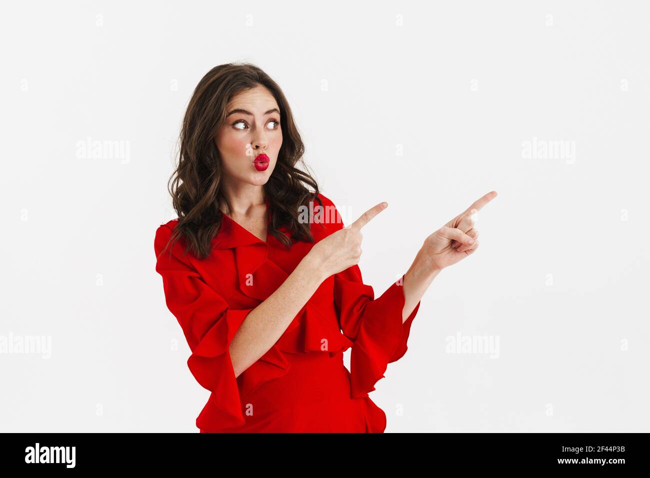 Surprised nice girl wearing red dress pointing fingers aside isolated ...