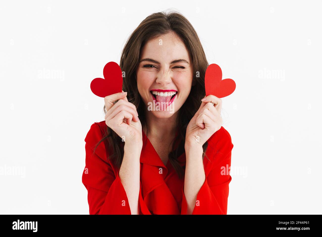 Cheerful beautiful girl winking while making fun with paper hearts ...