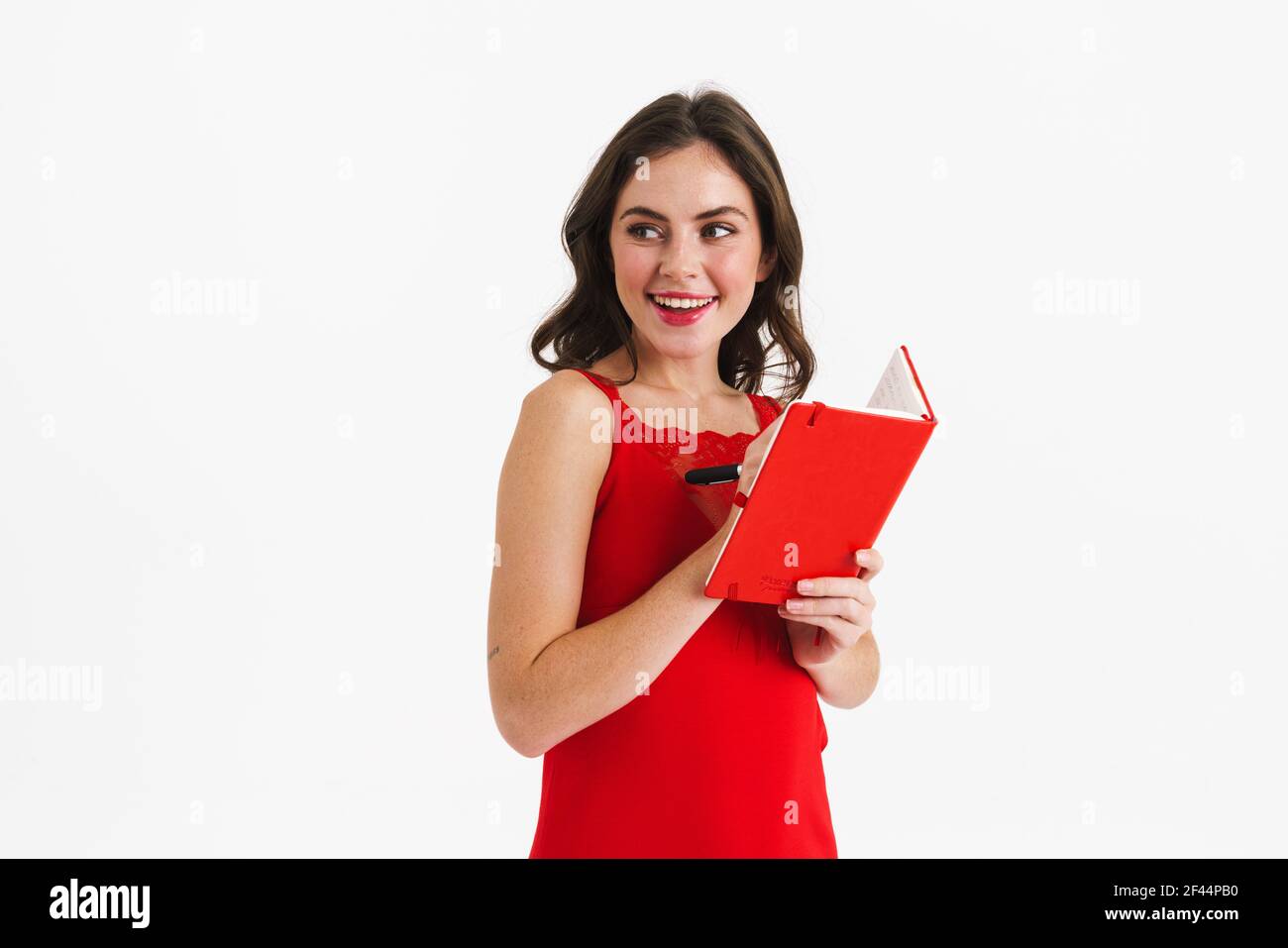Happy beautiful girl writing down notes in planner isolated over white ...