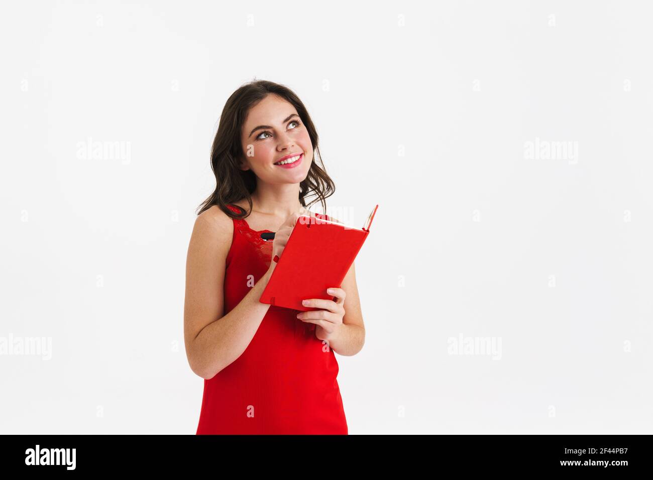 Happy beautiful girl writing down notes in planner isolated over white ...