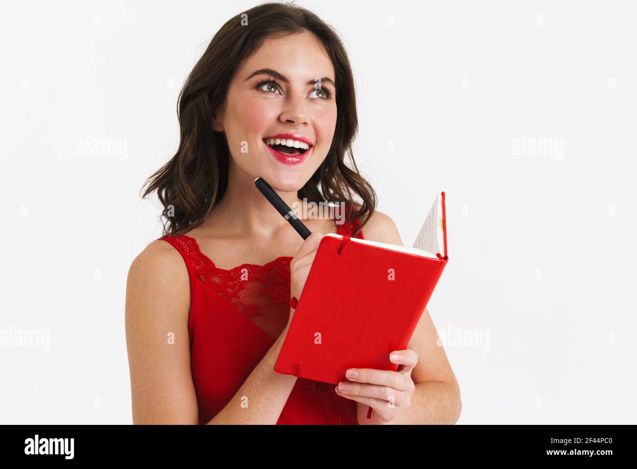 Happy beautiful girl writing down notes in planner isolated over white ...