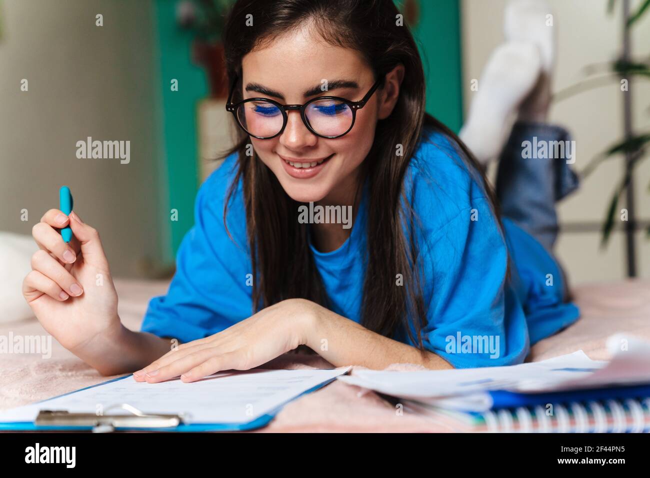 Lovely smart young girl studying while laying in bed Stock Photo - Alamy