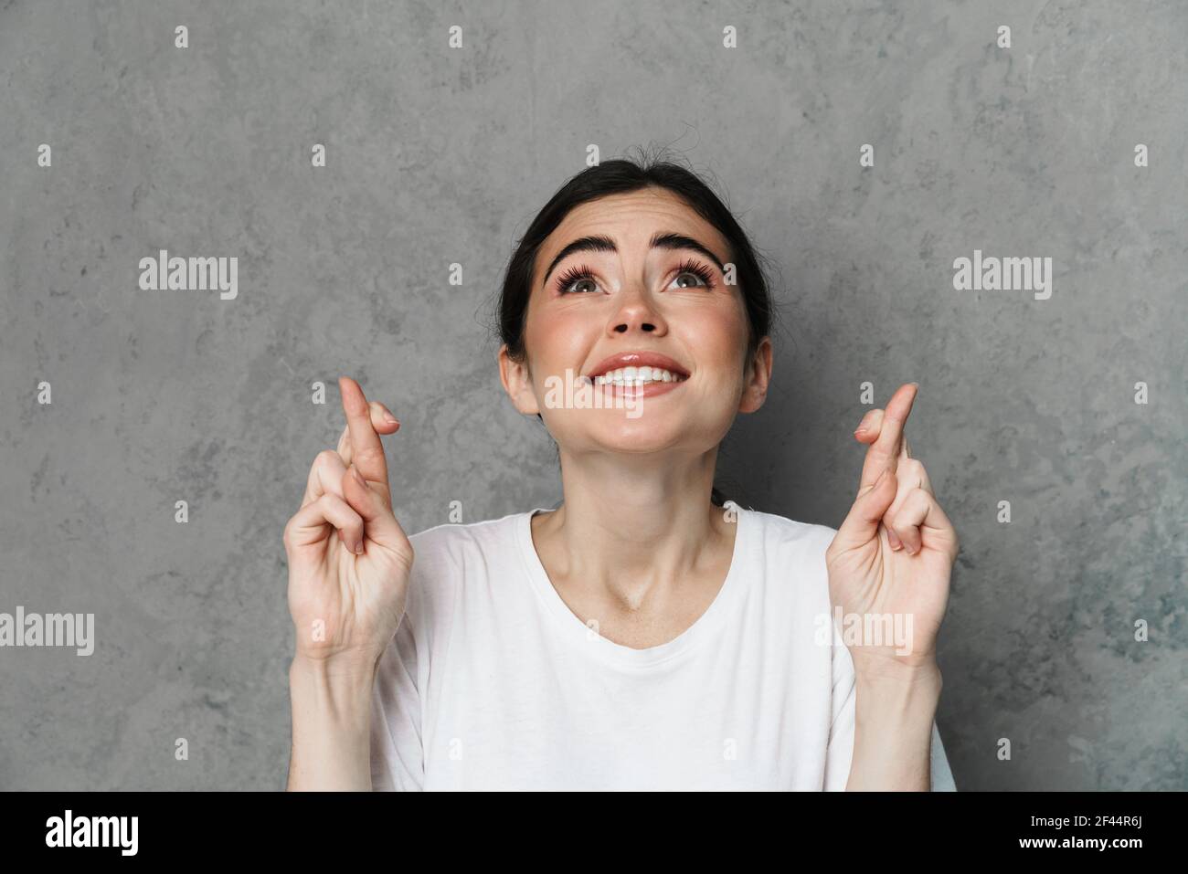 Worried smiling young woman begging for something putting hands ...