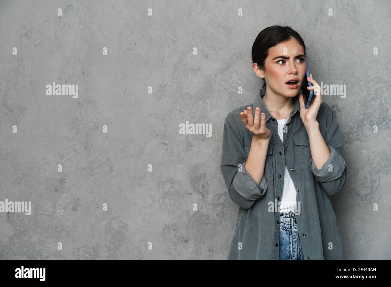 Annoyed woman having negative conversation isolated on gray. Distance ...