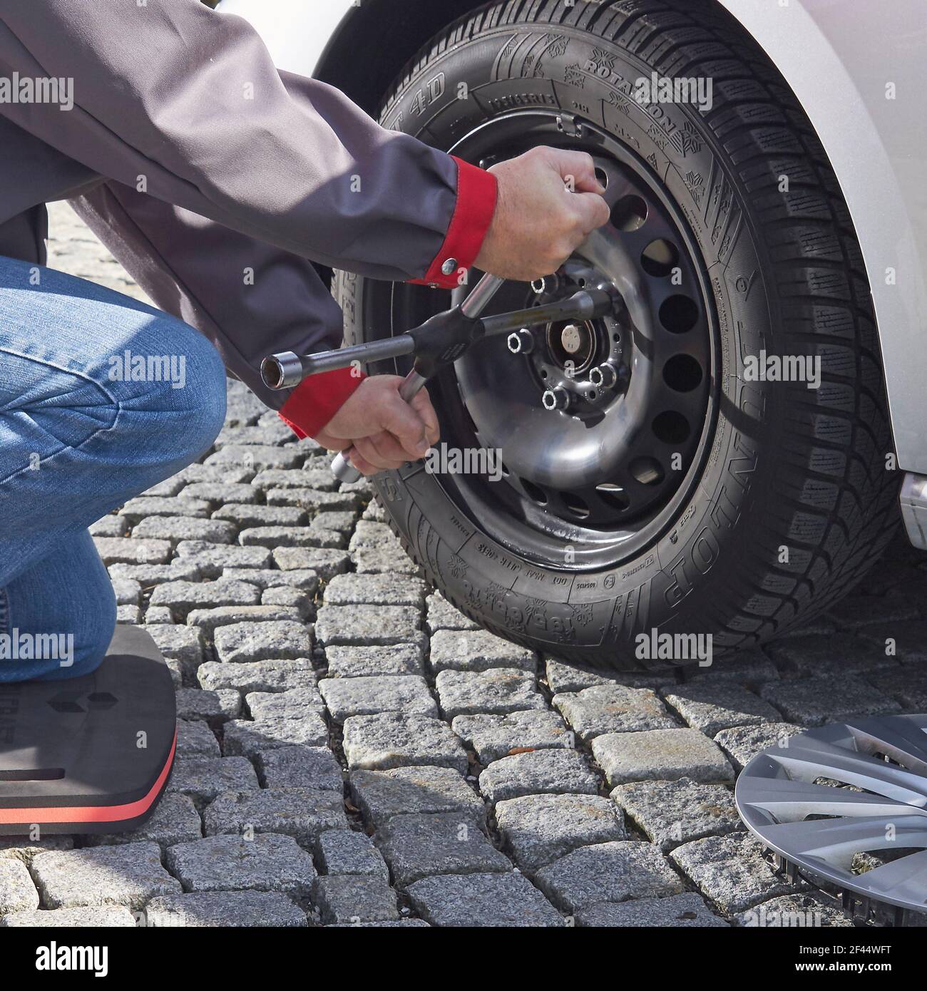 Man changing wheel on car outside, using wheel wrench Stock Photo - Alamy